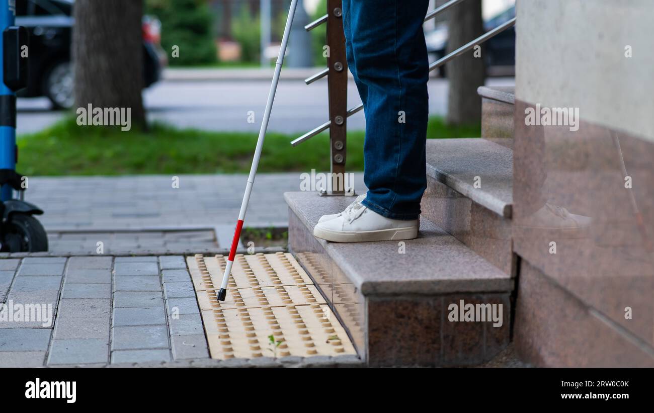 Close-up of female foot, walking stick and tactile tiles. Blind woman ...