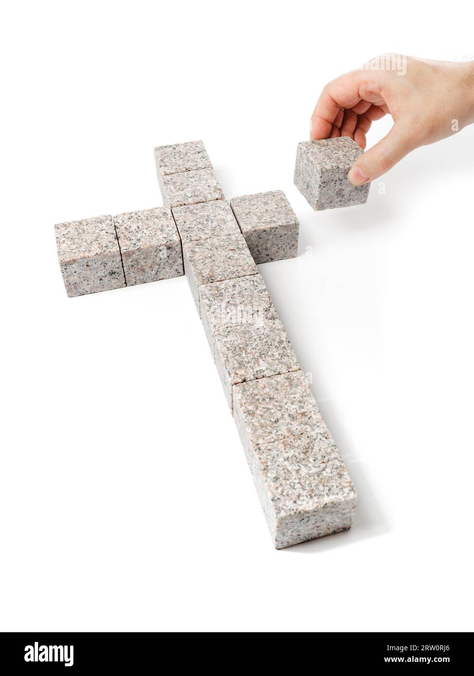 Man building a christian cross made of small blocks of granite rock ...