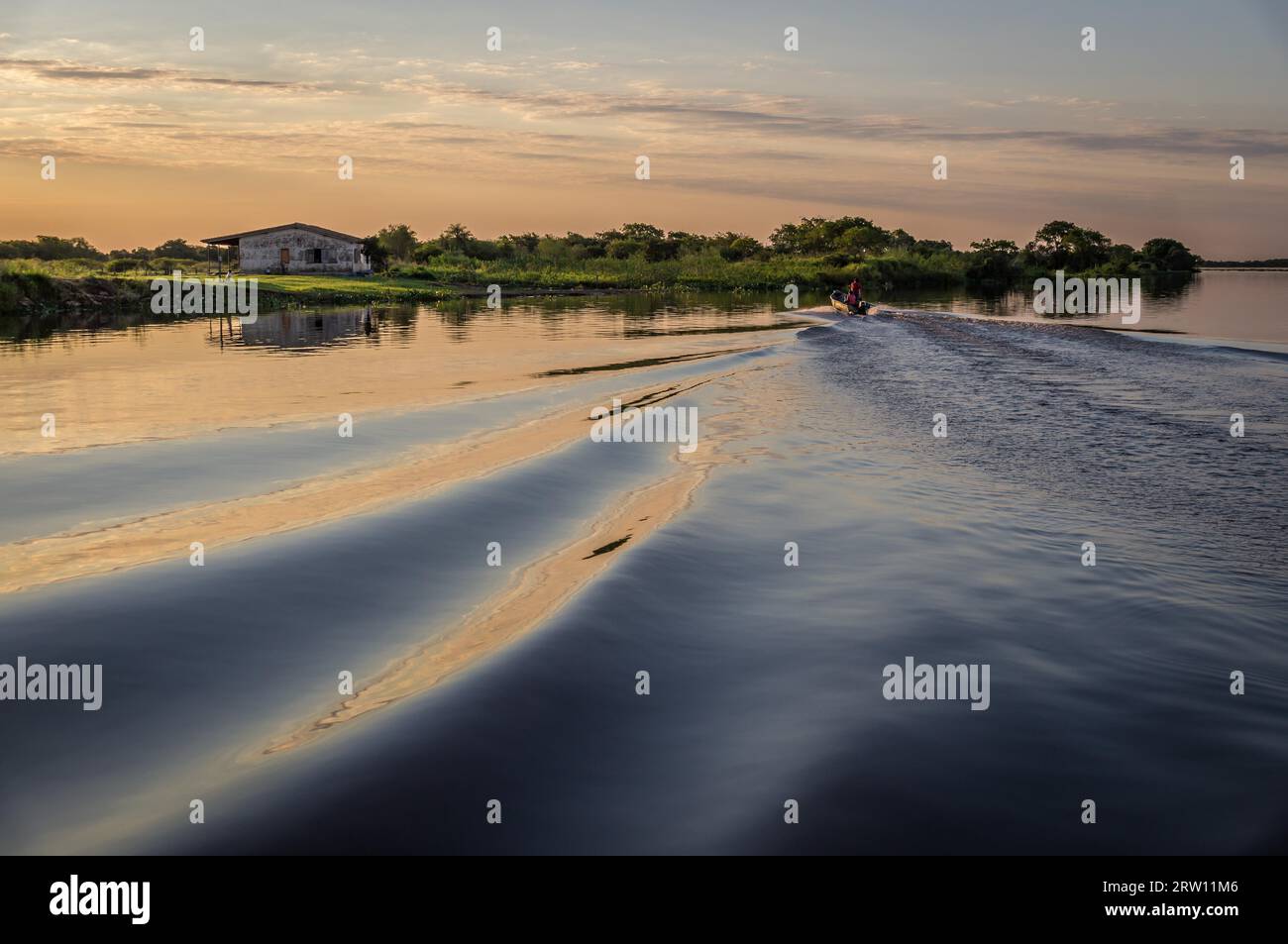 Small motor boat making waves at sunset at Rio Paraguay Stock Photo - Alamy