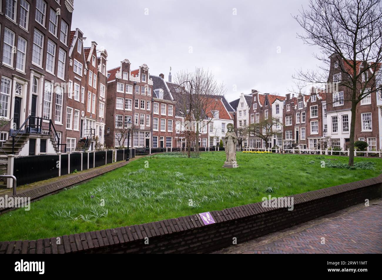 Old Dutch buildings of the Begijnhof surrounded by a park in Amsterdam ...