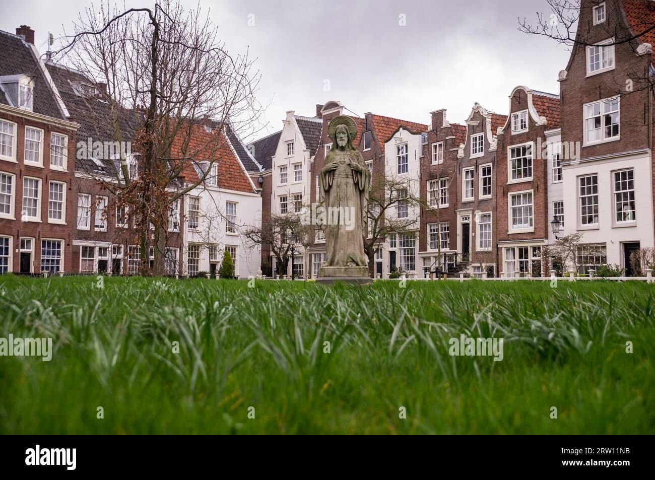 Old Dutch buildings of the Begijnhof surrounded by a park in Amsterdam ...