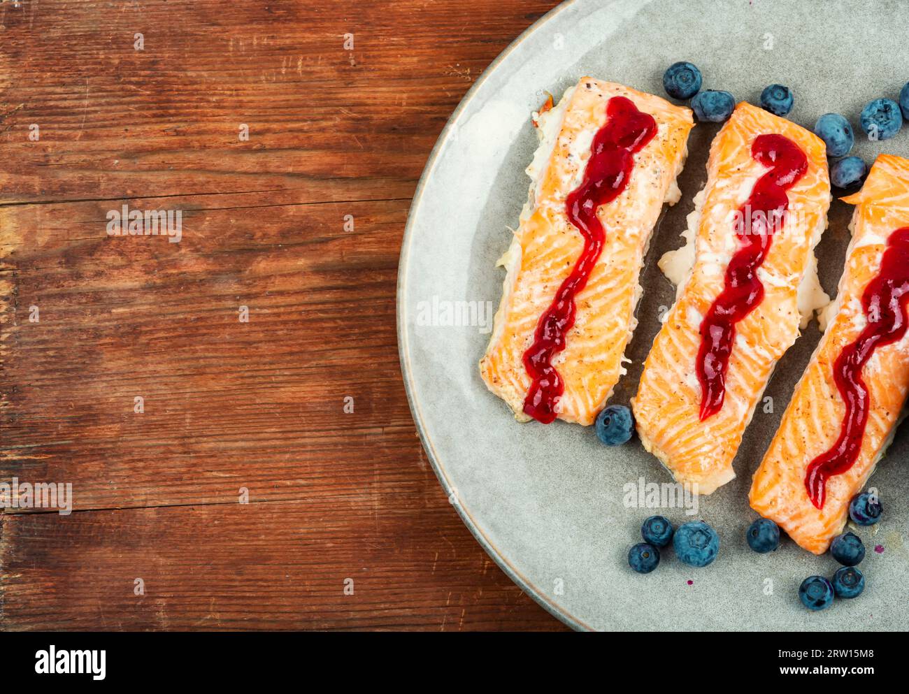 Baked salmon fillet with blueberry berry sauce on a rural wooden table ...