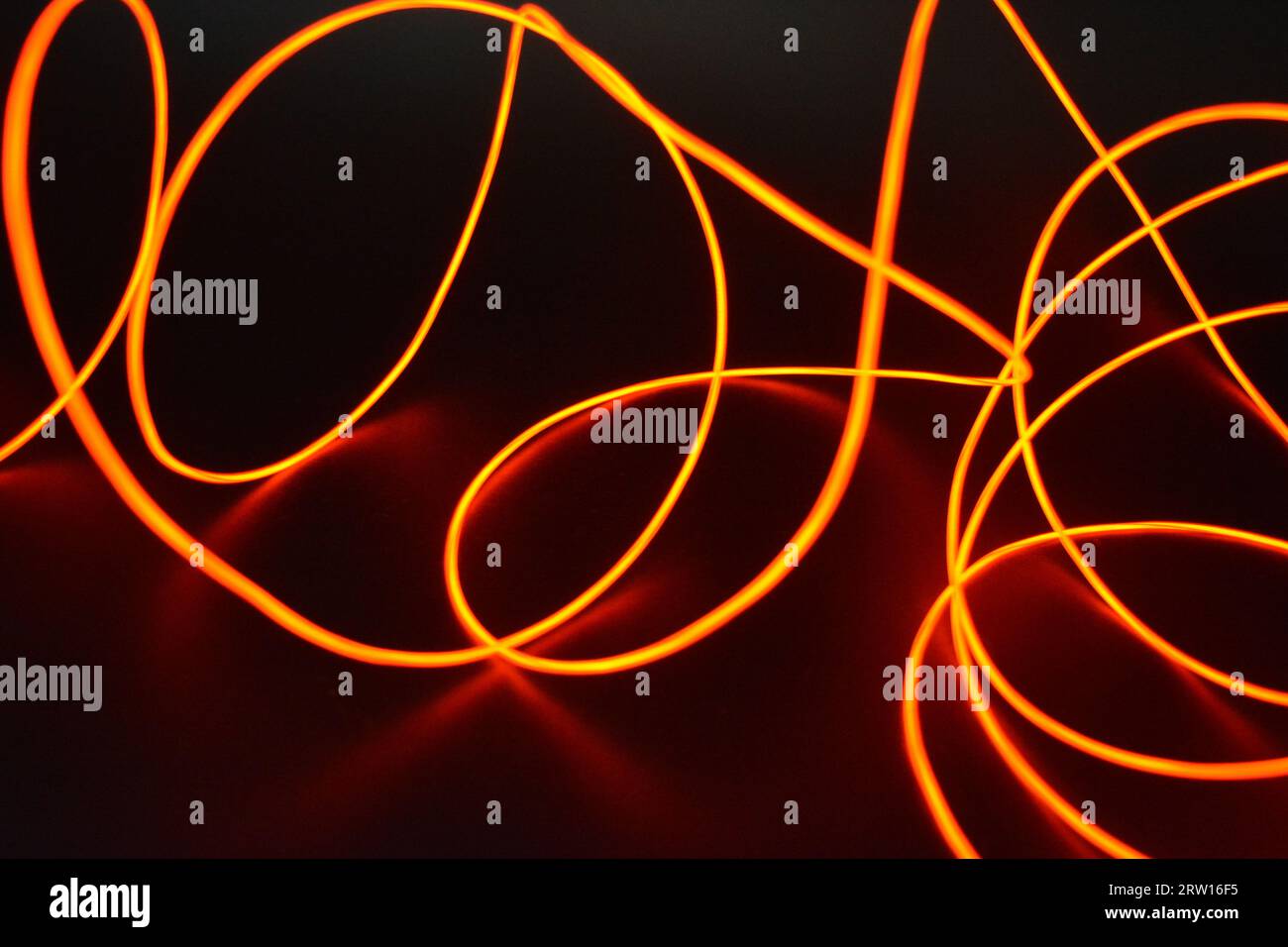 Unusual glowing background of chaotically stacked thin light wires, red ...