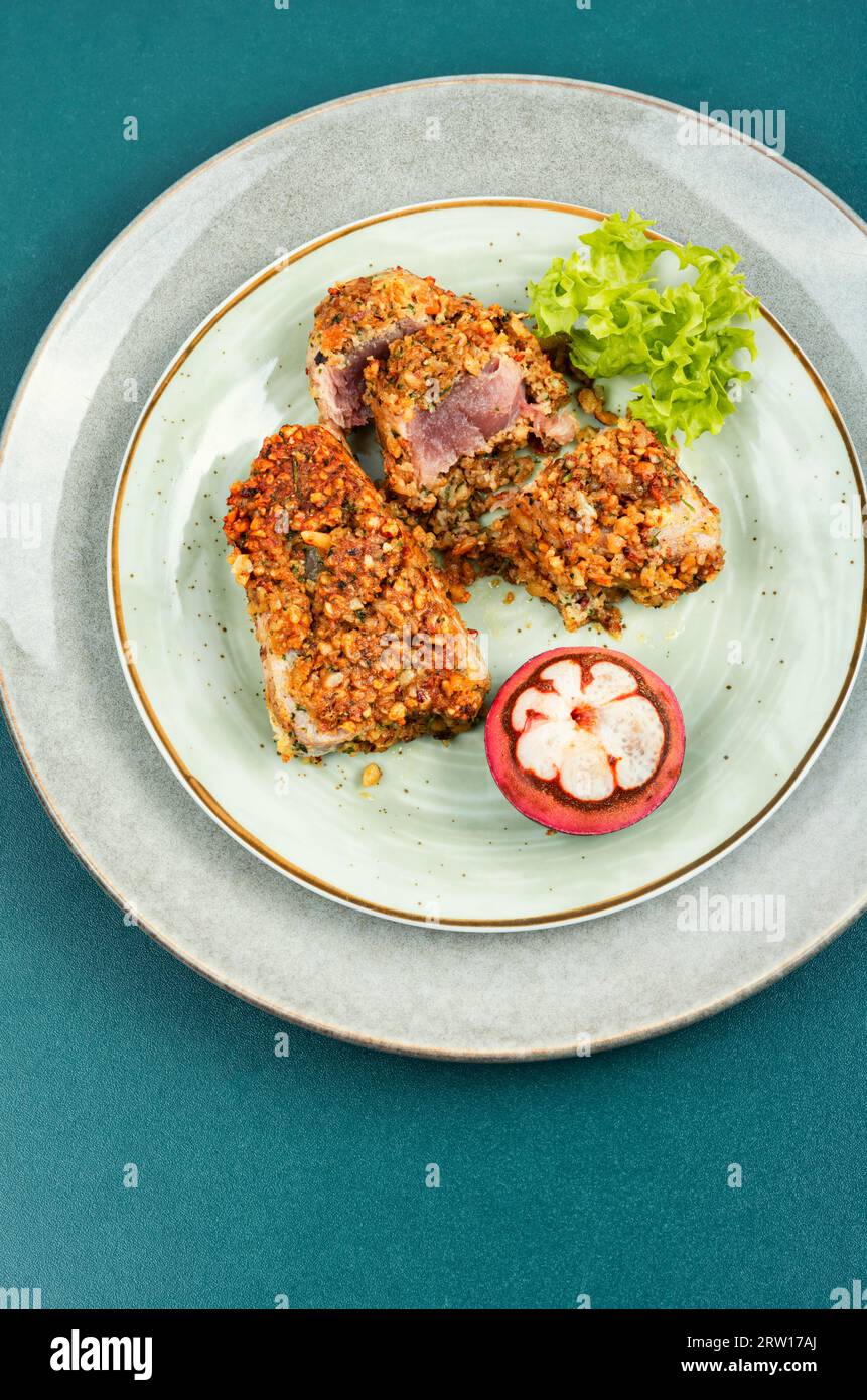 Cooked steak of baked tuna in a nut panic with a mangosteens. Fish ...