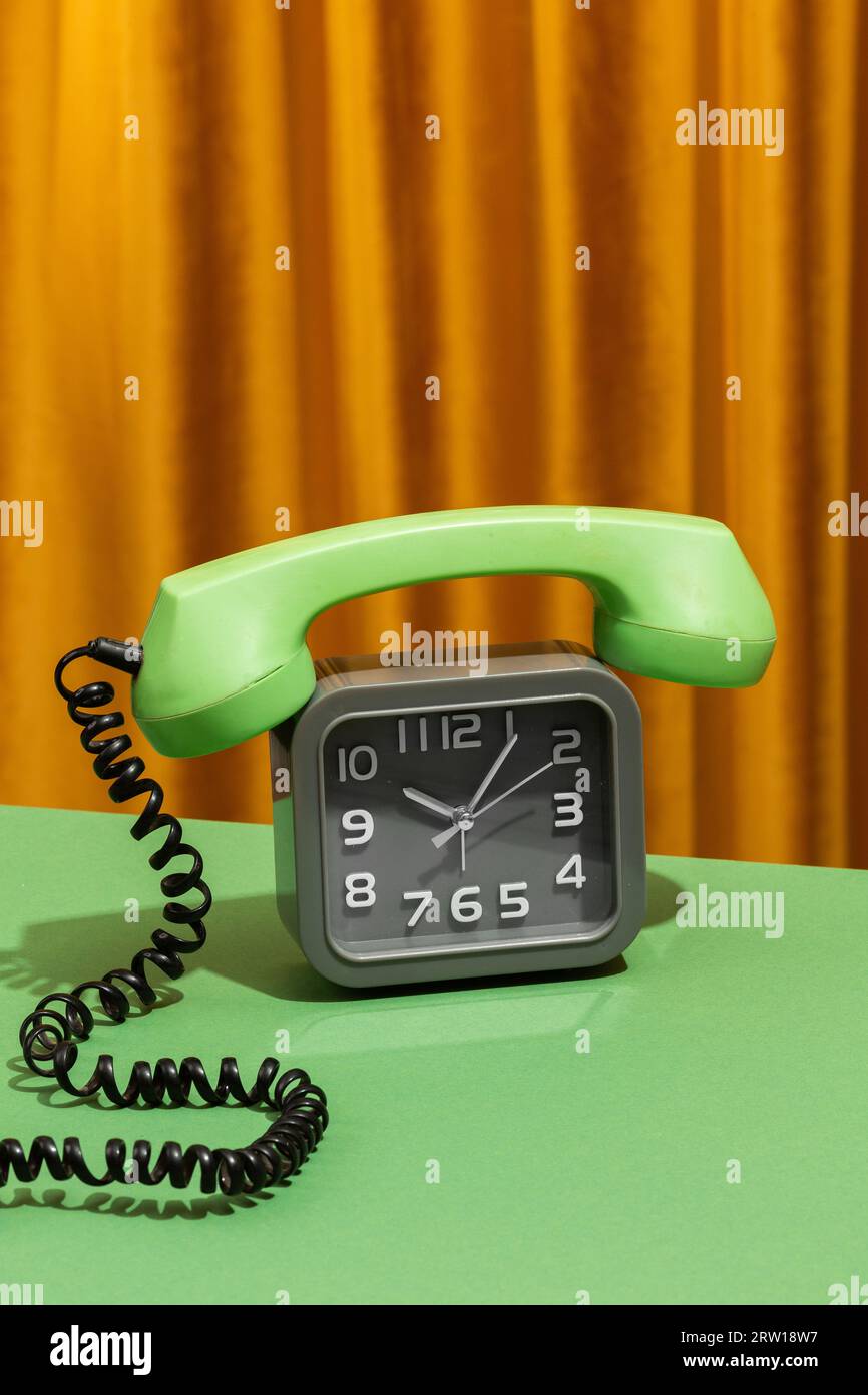 Vintage old clock with an old-fashioned rotary phone on a table in a ...