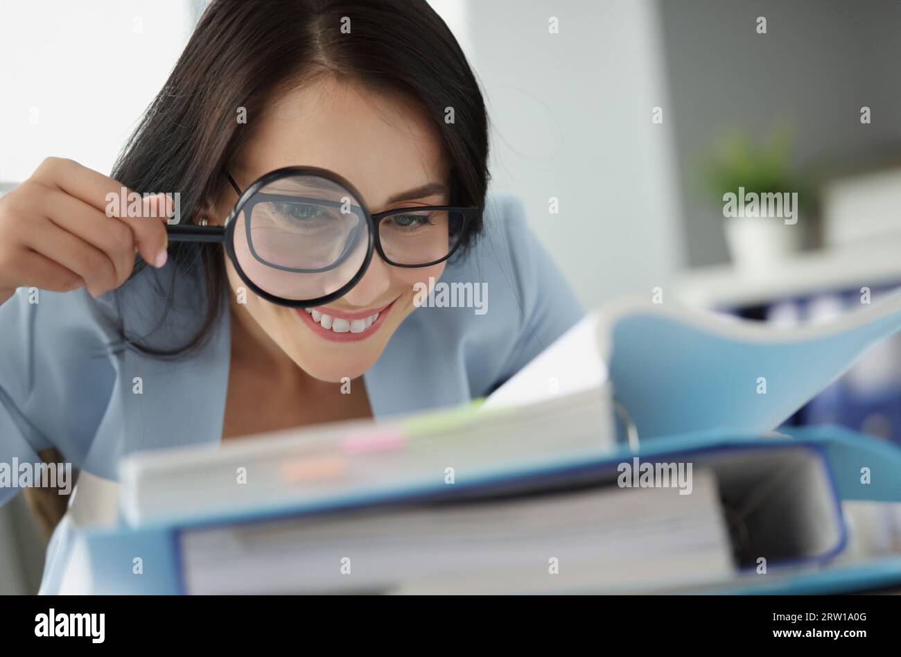 Portrait of young beautiful woman examining documents through ...