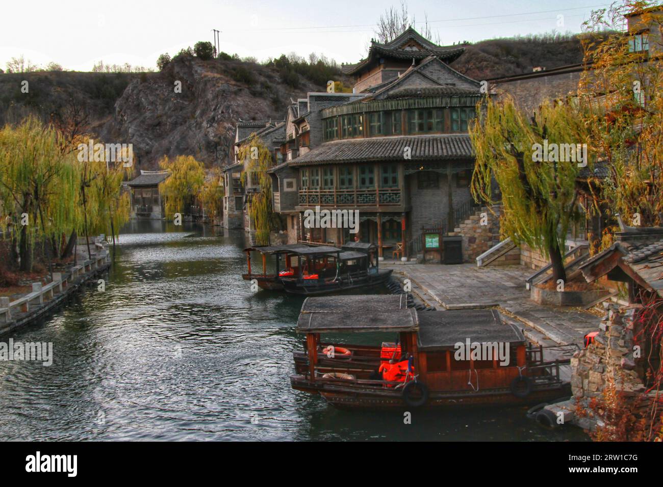 Capture the serene charm of a river winding through traditional houses ...