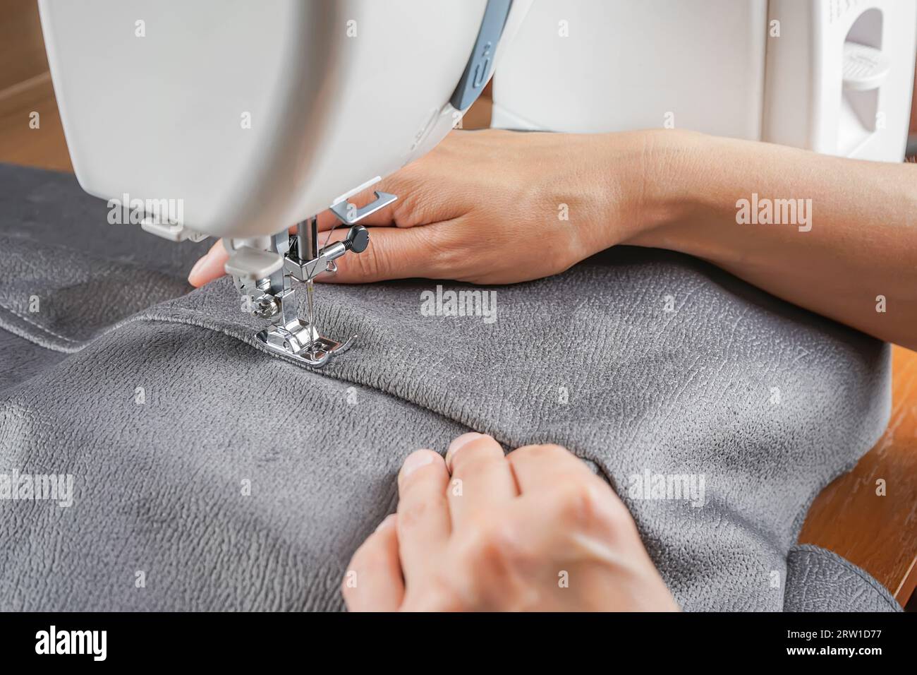 Tailor hands stitching gray fabric on modern sewing machine at ...