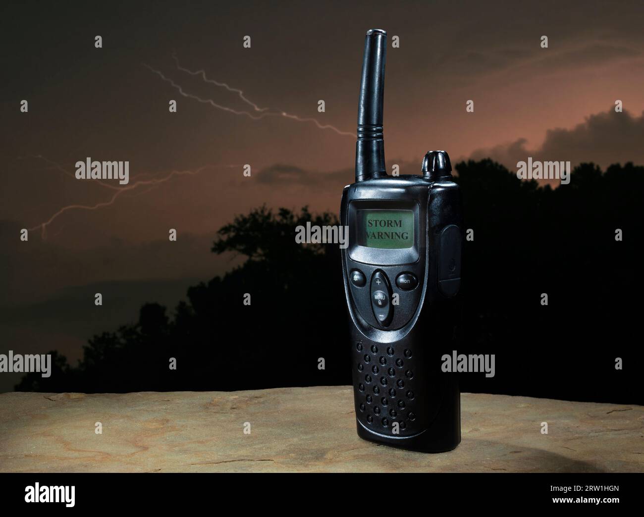 Handheld two way radio with a storm warning flashing on the screen with ...