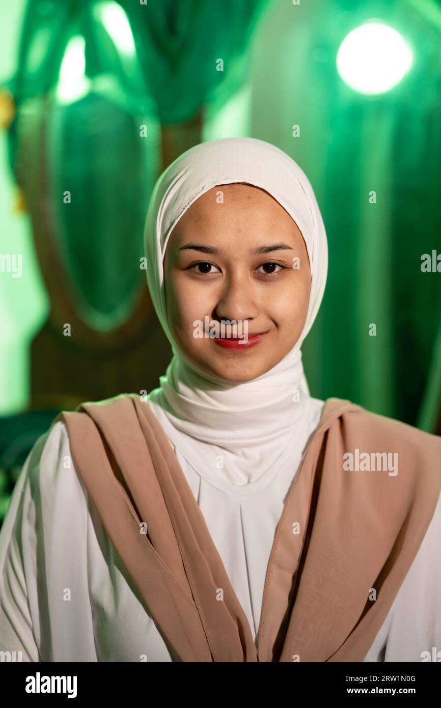 a Muslim woman with a white headscarf and white clothes smiling very ...