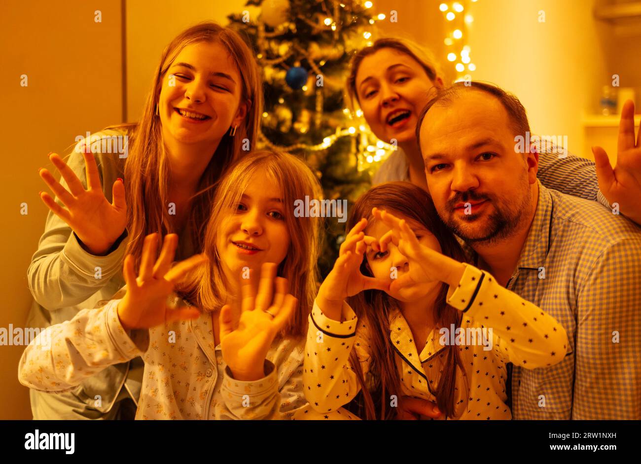 A large family in pajamas is celebrating Christmas at home. Parents and ...