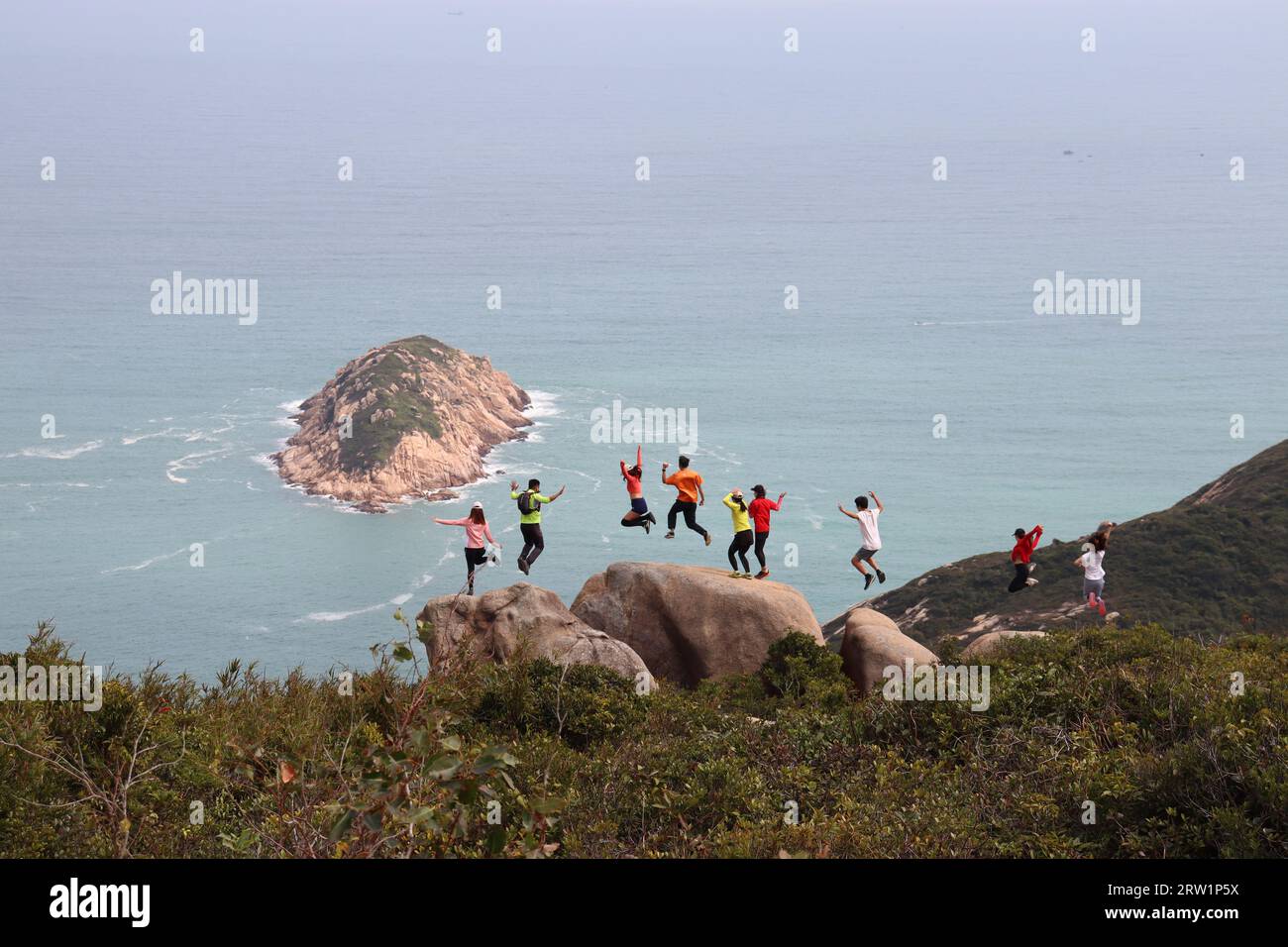 Hong Kong life - people jumping at the edge of a rock Stock Photo - Alamy