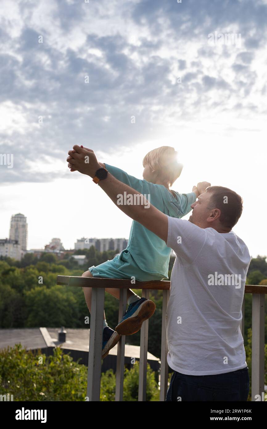 dad and son holding hands look at city in front of them. concept of ...