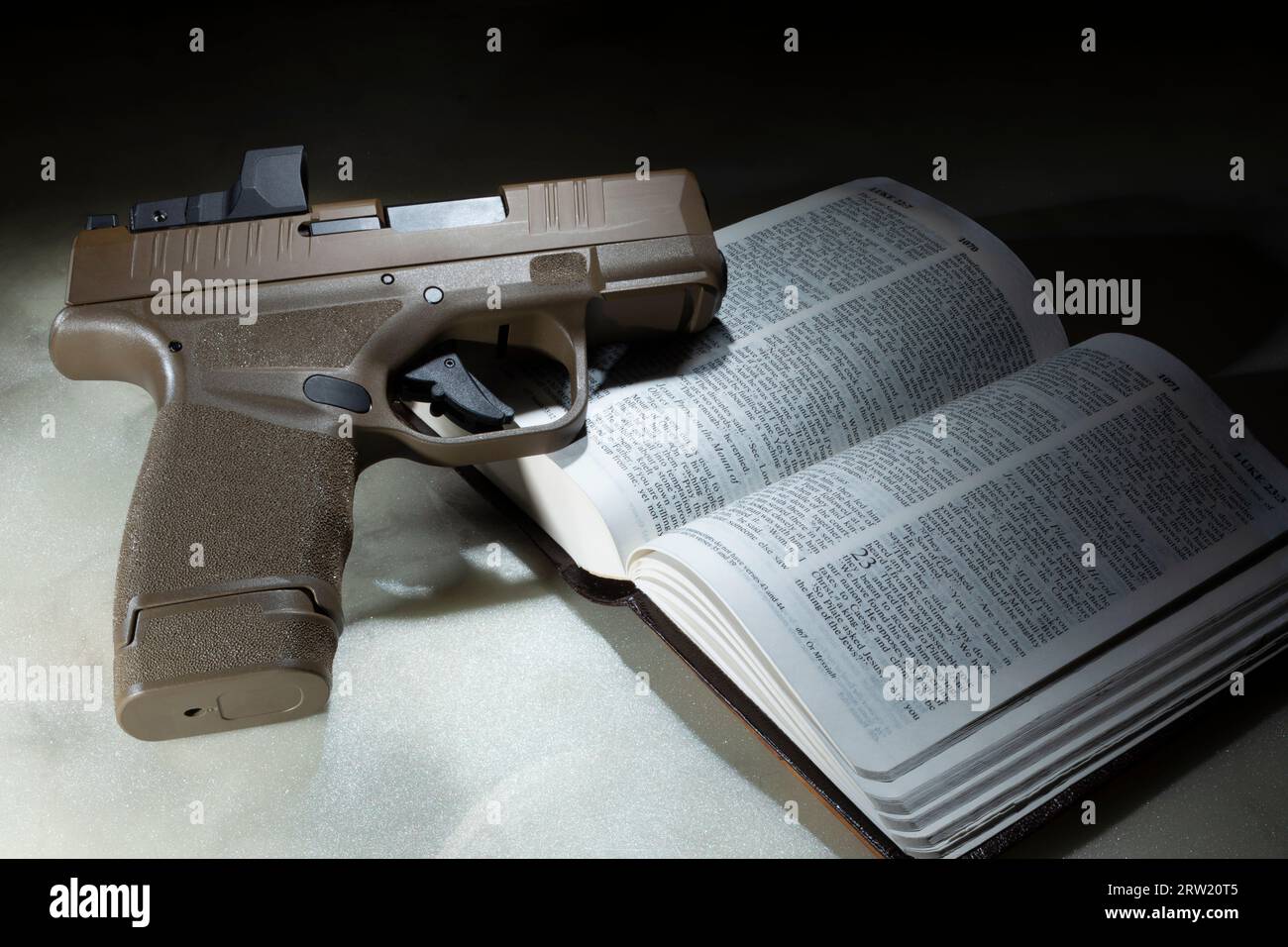Brown semi-automatic 9 mm pistol with a bible underneath open to the ...