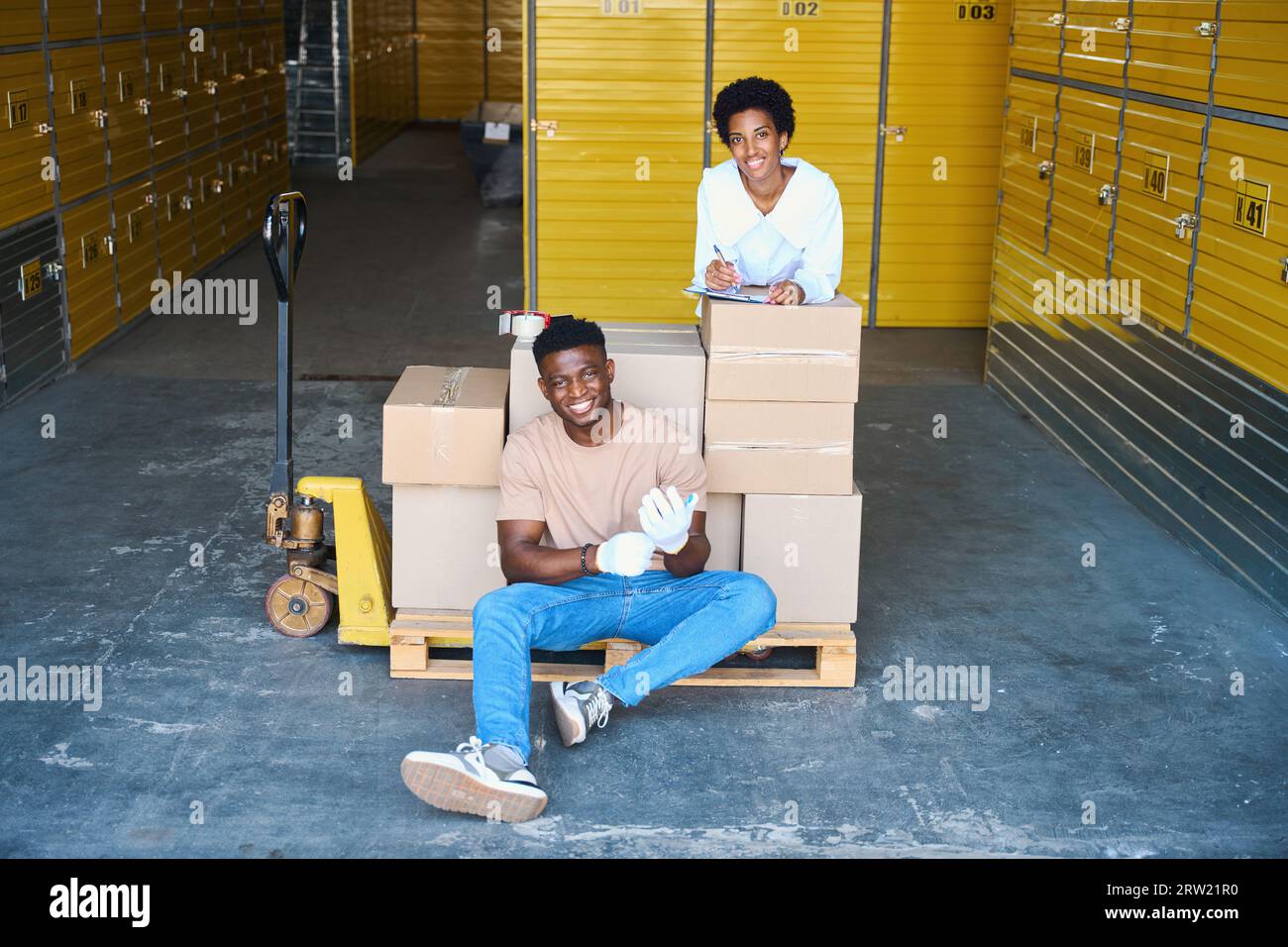 Young warehouse employees, a female manager and loader, at workplace ...