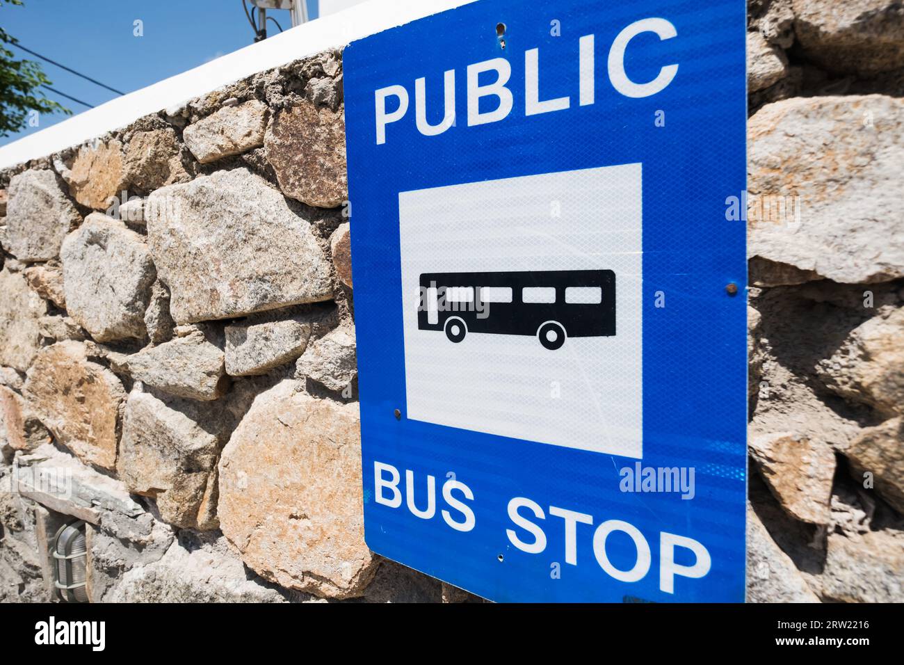 Public bus stop sign placed on a stone wall Stock Photo - Alamy