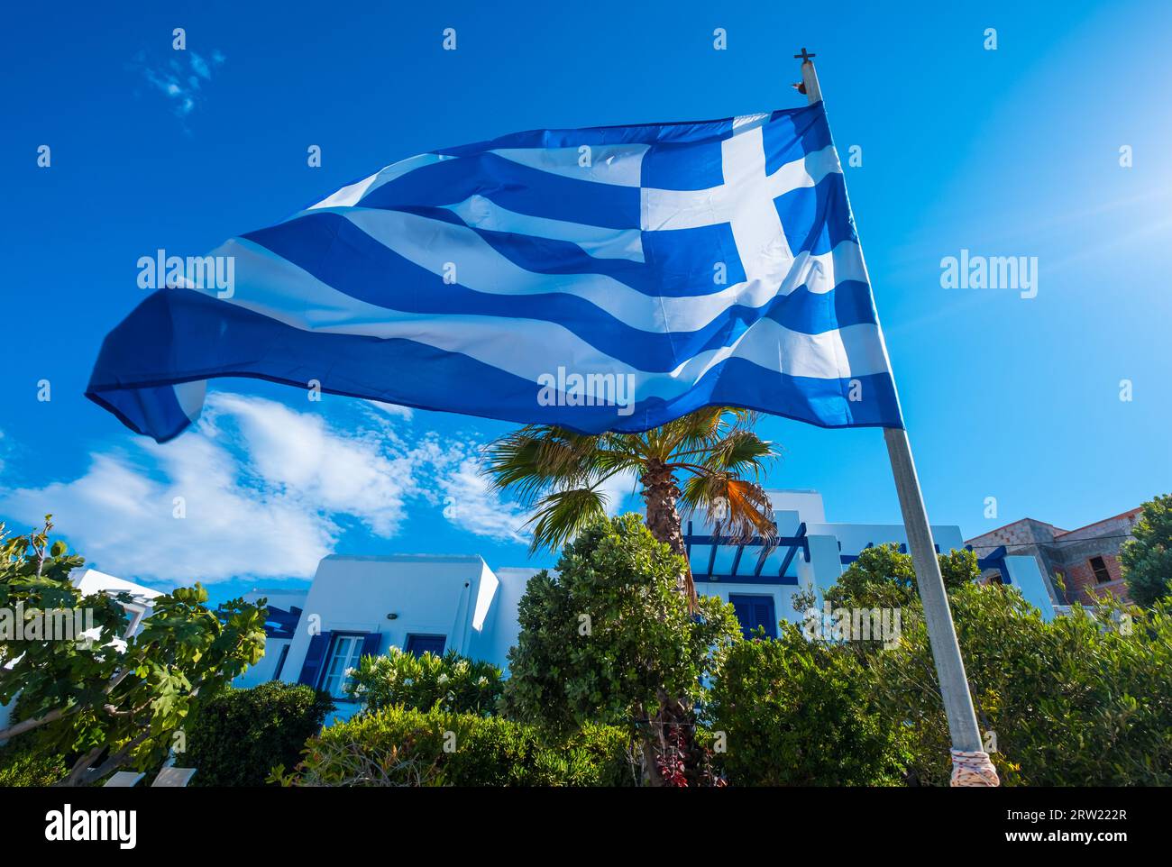 Greece flag on flagpole waving on street background Stock Photo - Alamy