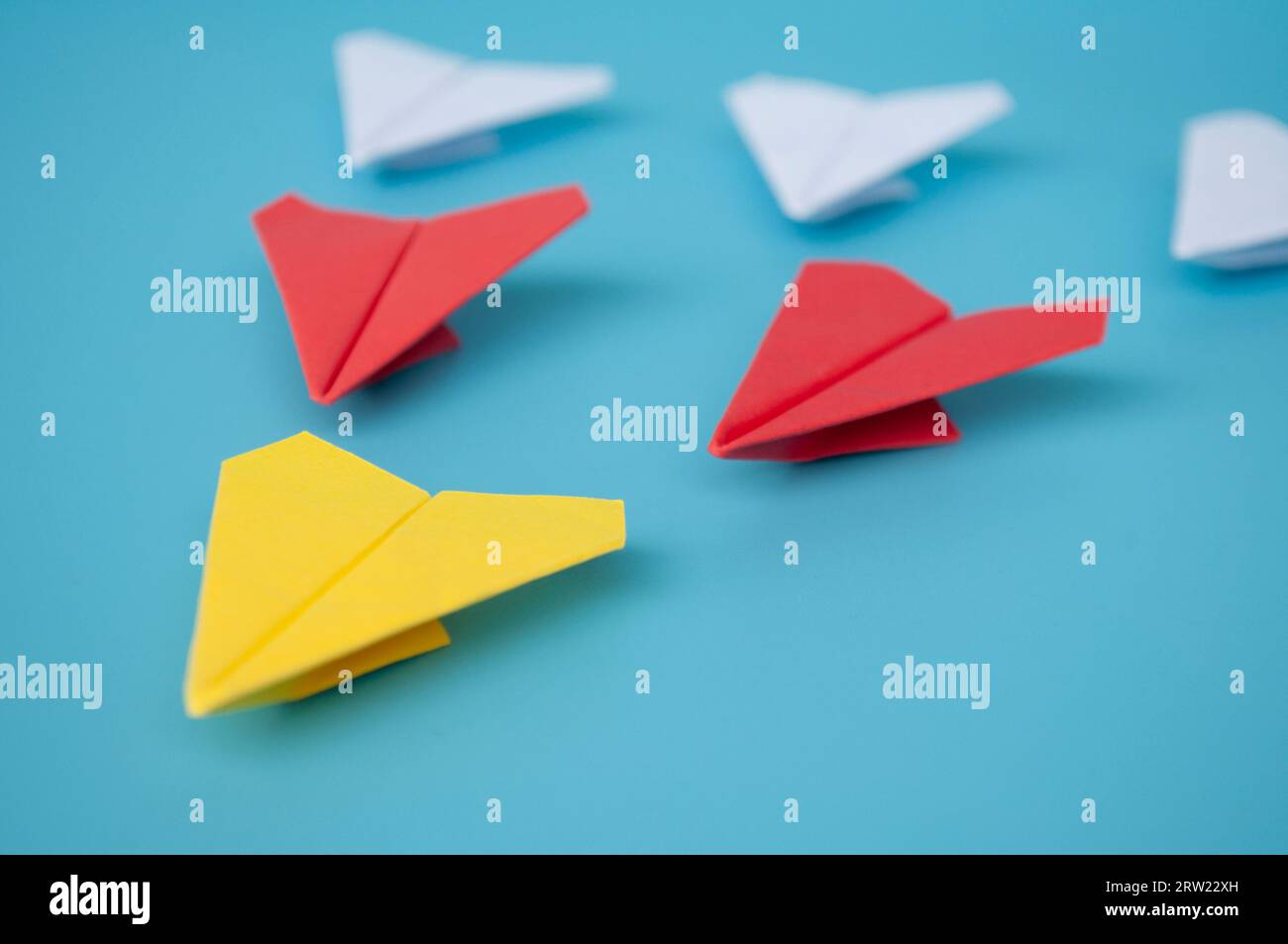 Side view of yellow paper airplane origami leading red and white paper ...