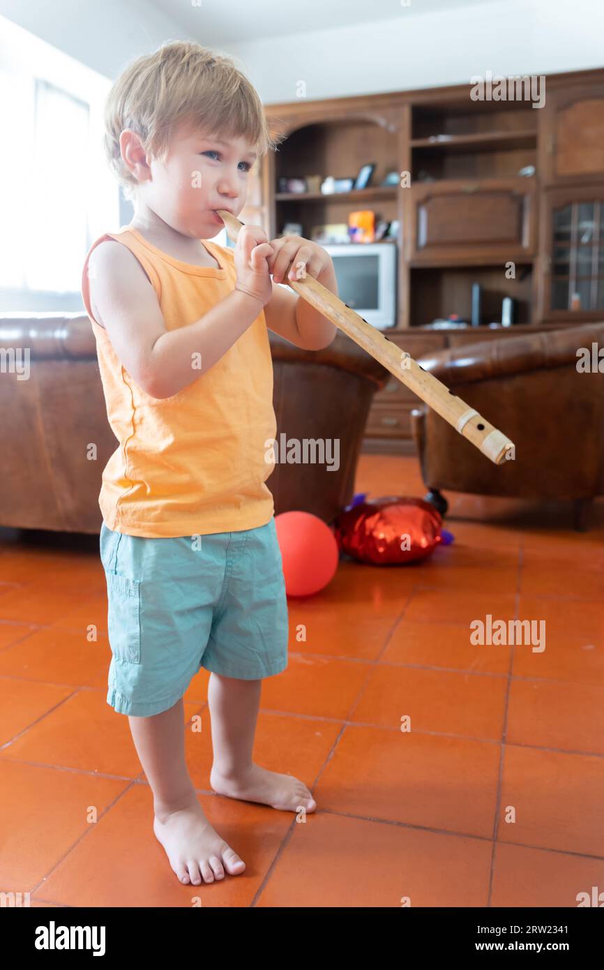 Little boy blowing the flute at home. Vertical shot Stock Photo - Alamy