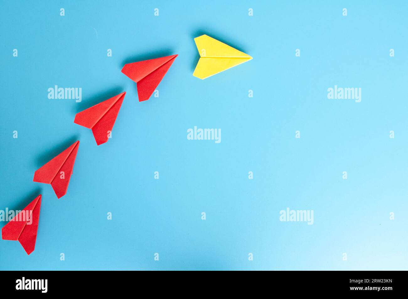 Top view of yellow paper airplane origami leading red paper airplanes ...