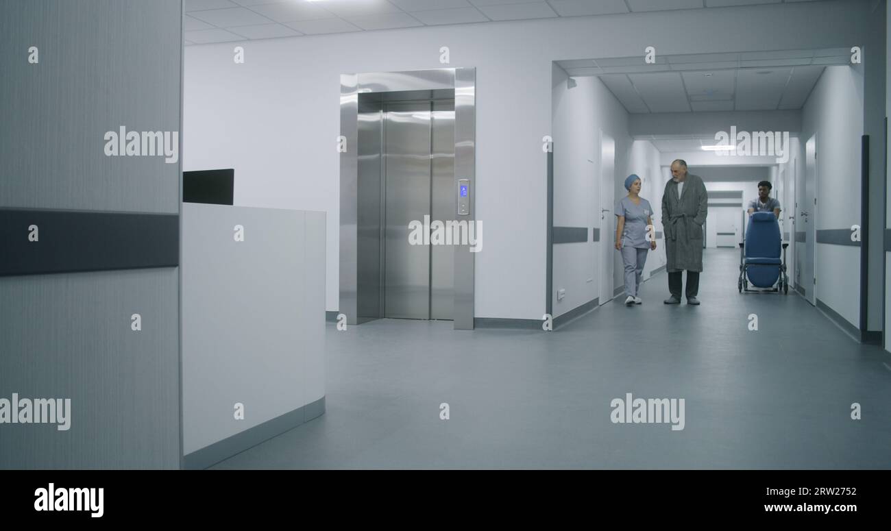 Nurse with old patient wait for elevator in medical center hallway ...