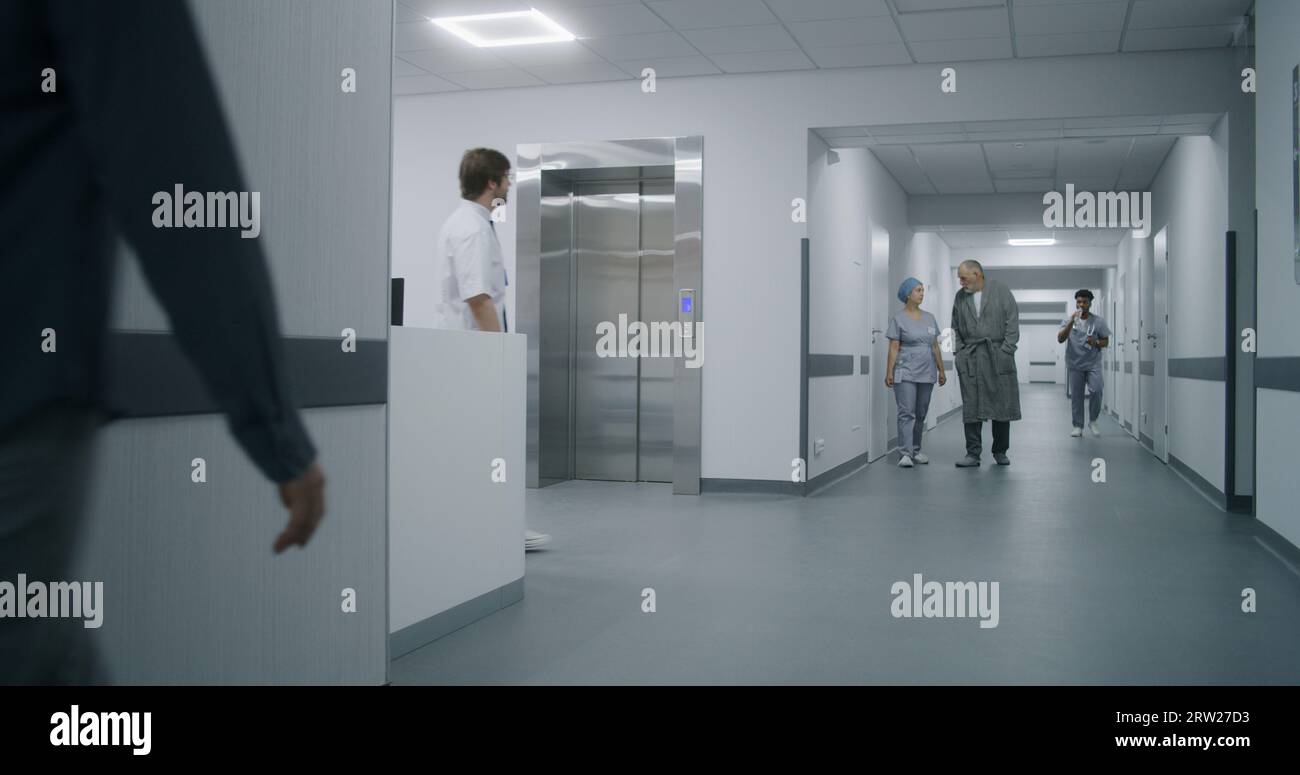 Nurse with old patient wait for elevator in medical center hallway ...