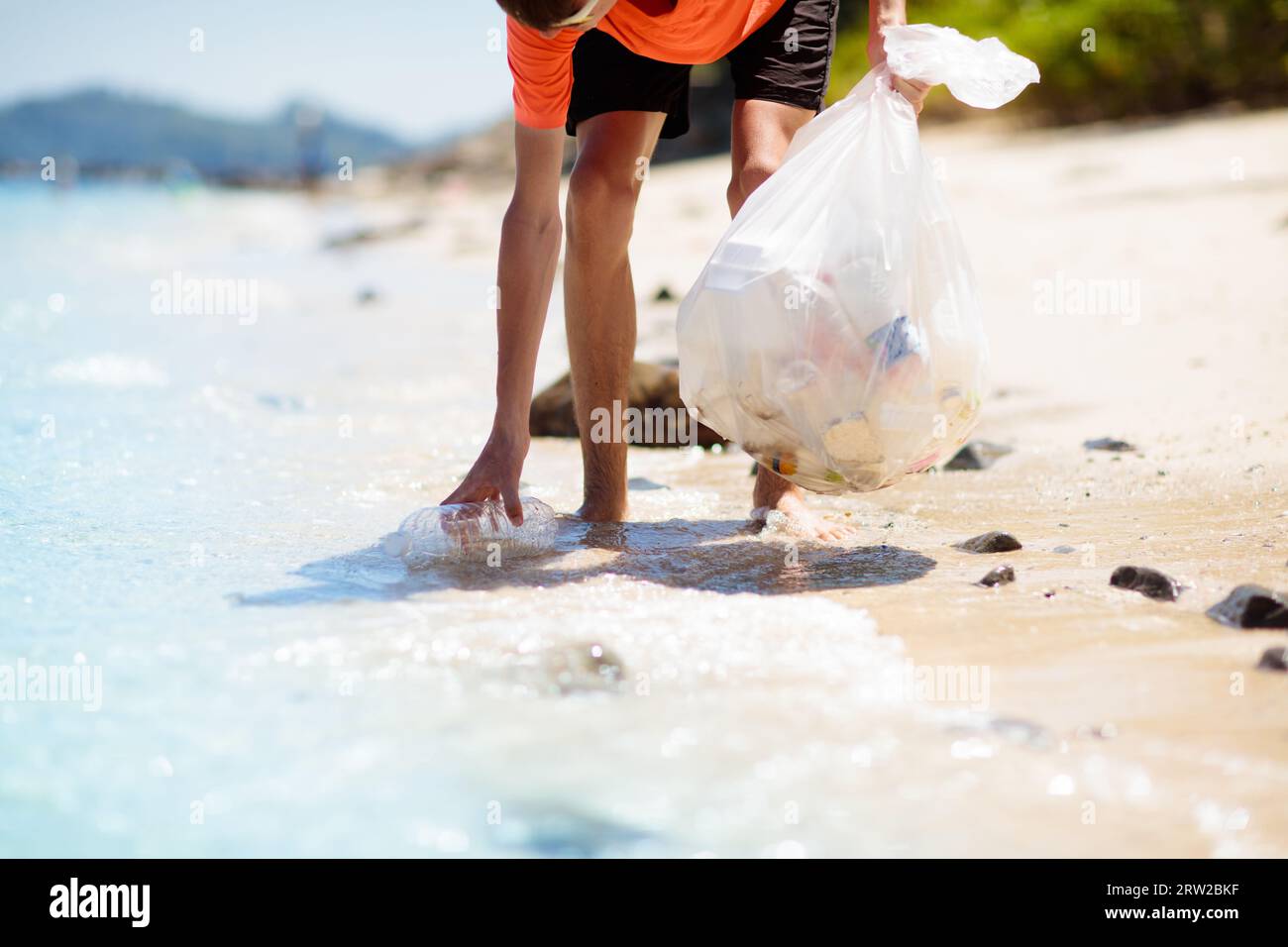 Plastic garbage. Sea and ocean pollution. Beach clean up. Young man ...