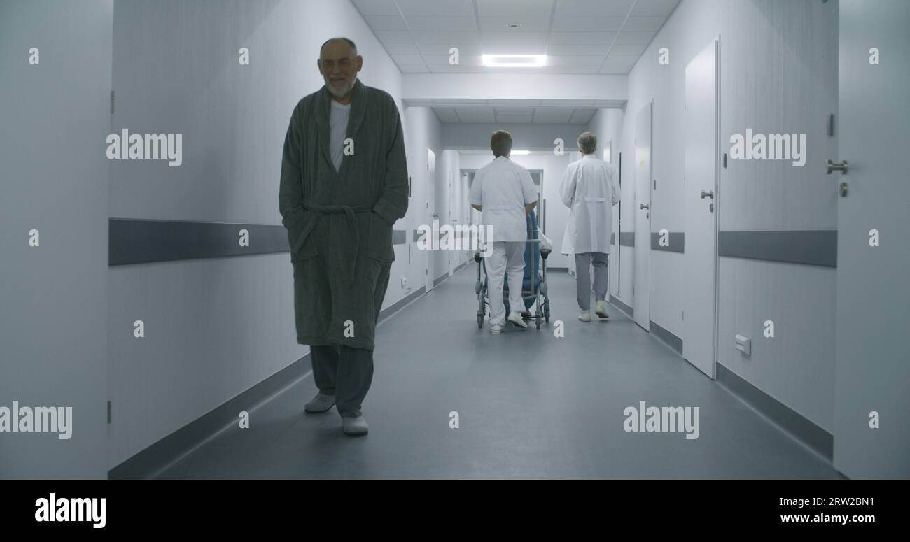 Multiracial medical staff in uniform walk clinic corridor. Elderly ...