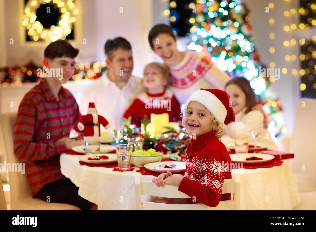 Family with children eating turkey Christmas dinner at fireplace and ...