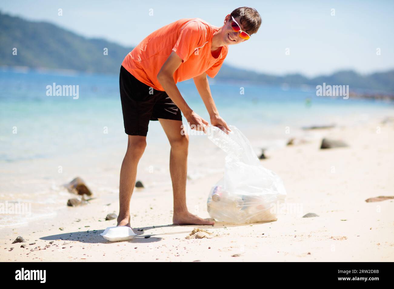 Plastic garbage. Sea and ocean pollution. Beach clean up. Young man ...