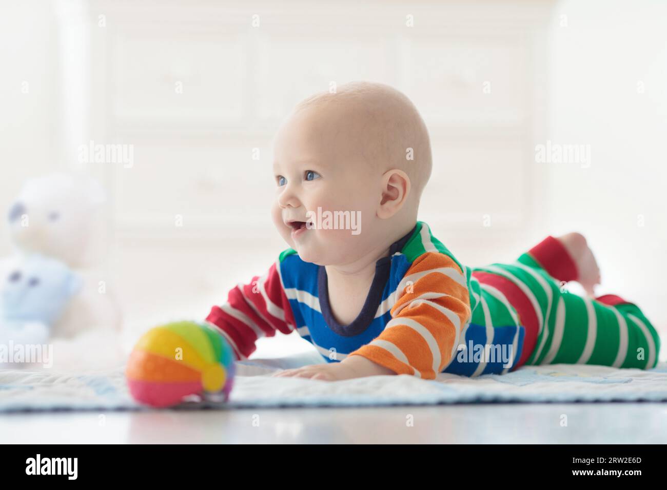 Adorable baby boy learning to crawl and playing with colorful rainbow ...