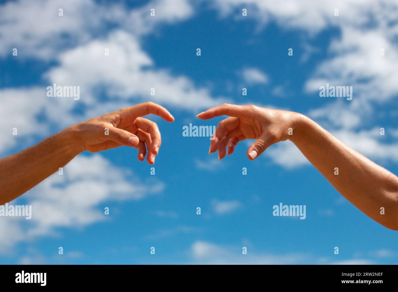 Two hands, one of a man and the other of a woman, meeting their fingers ...