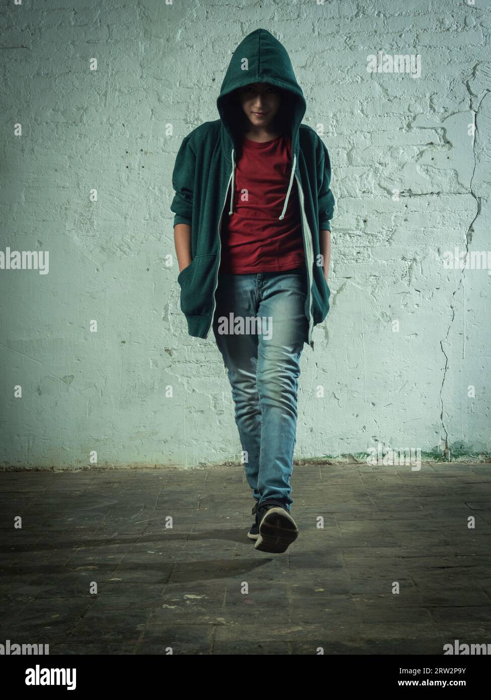 Boy walking straight towards the camera with hoodie untied and hood up ...