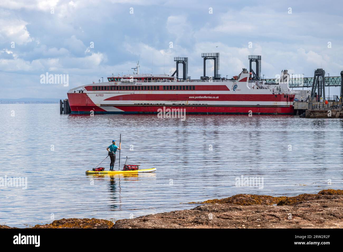 Woman water paddling and MV Alfred, Pentland Ferries, from Brodick to ...