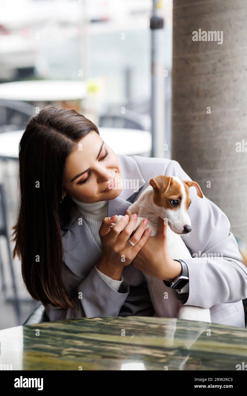 Caucasian woman and jack russell terrier look at the cake with a candle ...