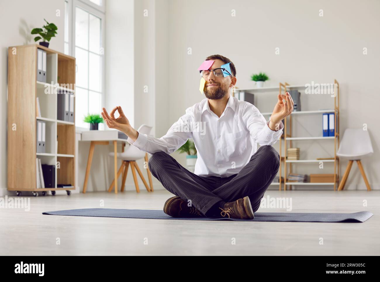 Funny man with sticky notes on face sitting on floor in office, doing ...