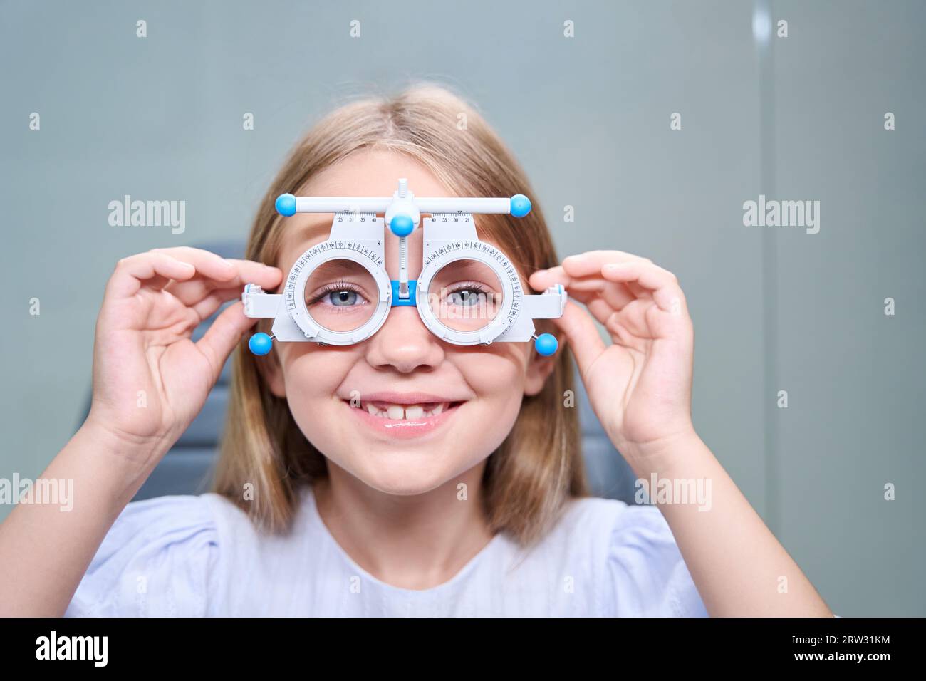 Cheerful little girl undergoing eye exam with refraction test Stock ...