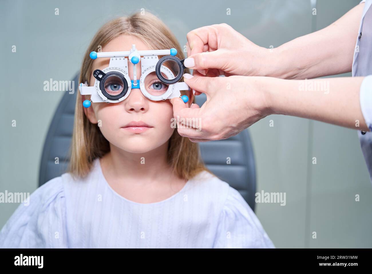 Experienced optometrist conducting subjective refraction test on little ...