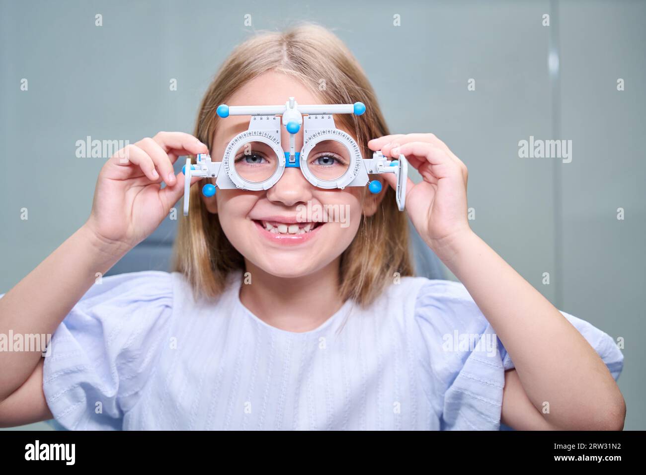Smiling young patient taking subjective refraction test at eye clinic ...