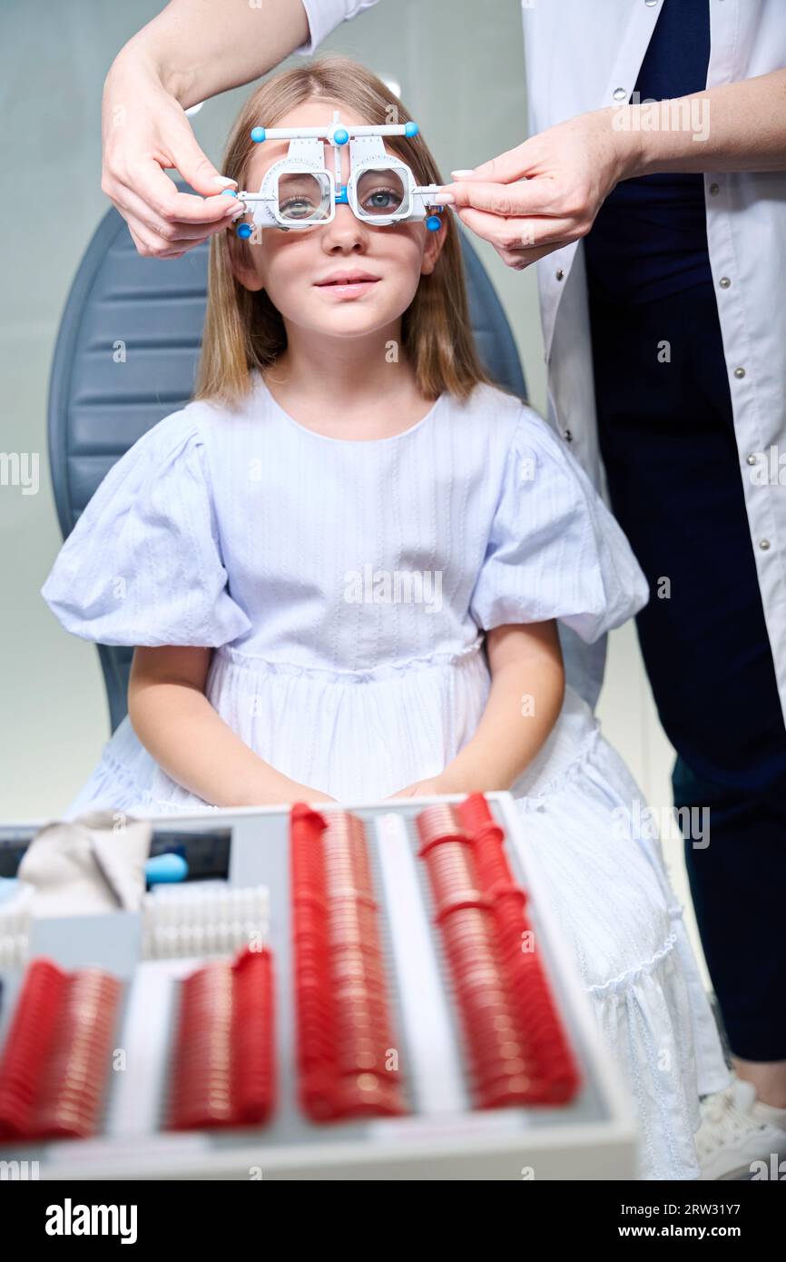 Tranquil little girl taking subjective refraction test in ...