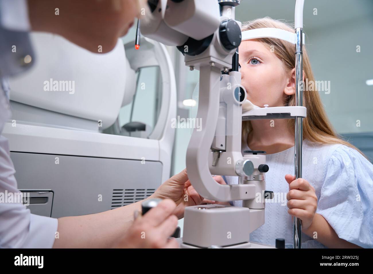 Licensed ophthalmologist conducting ocular examination of little girl ...