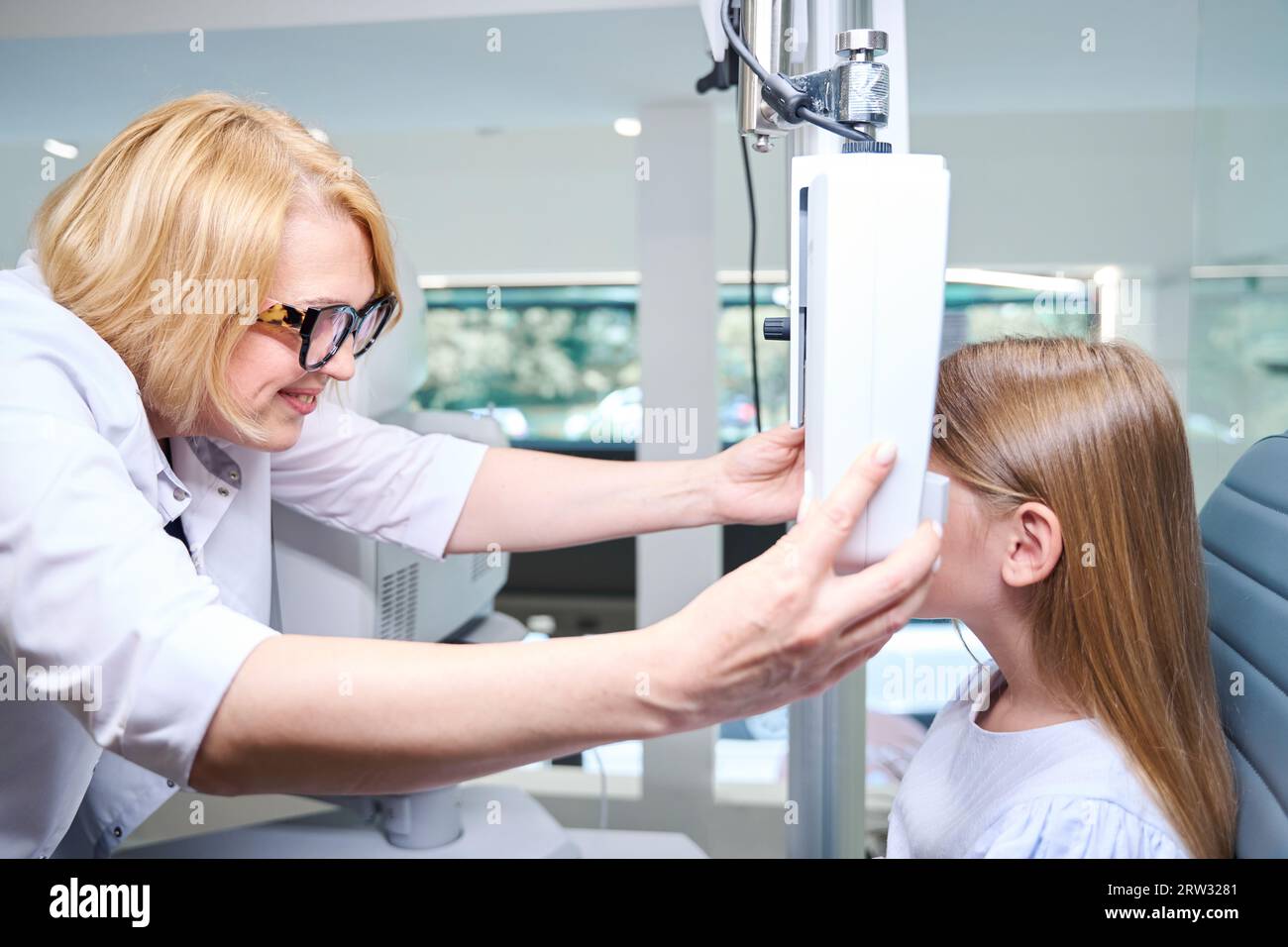 Cheerful eye doctor preparing little girl for binocular vision test ...