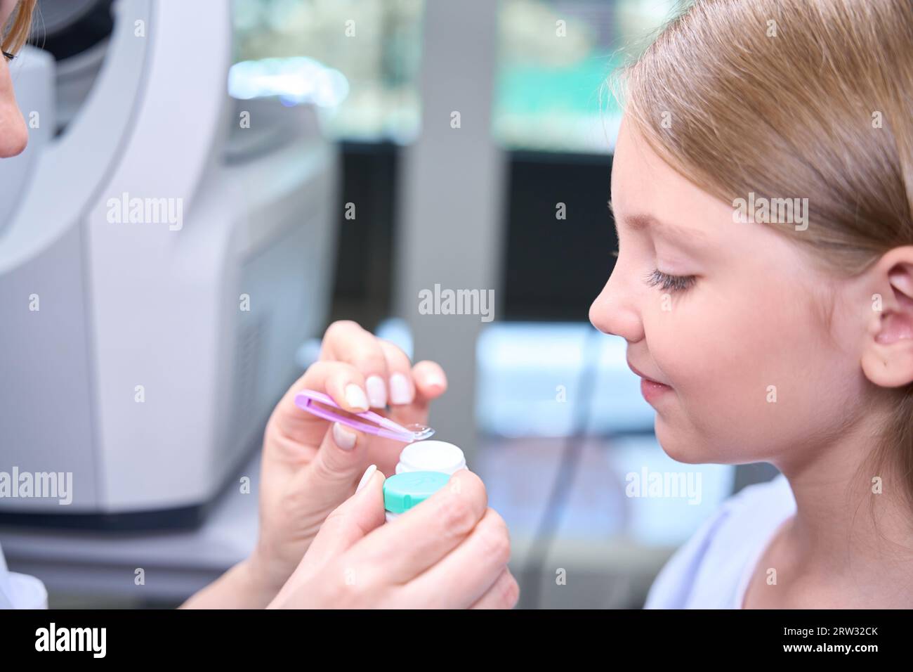 Ophthalmic optician demonstrating corrective lenses to child during ...