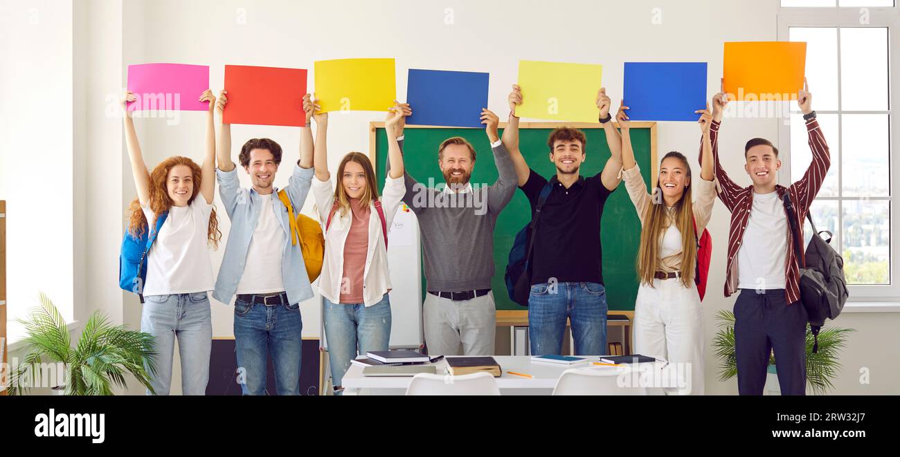 Happy students and their professor stand in row and hold blank sheets ...