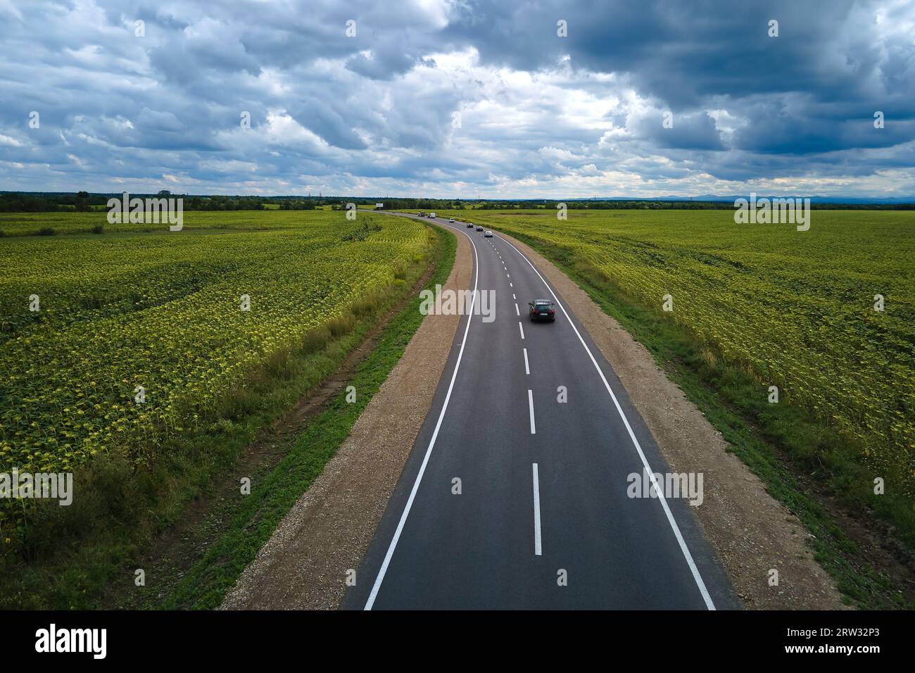 Aerial view of intercity road between green agricultural fields with ...