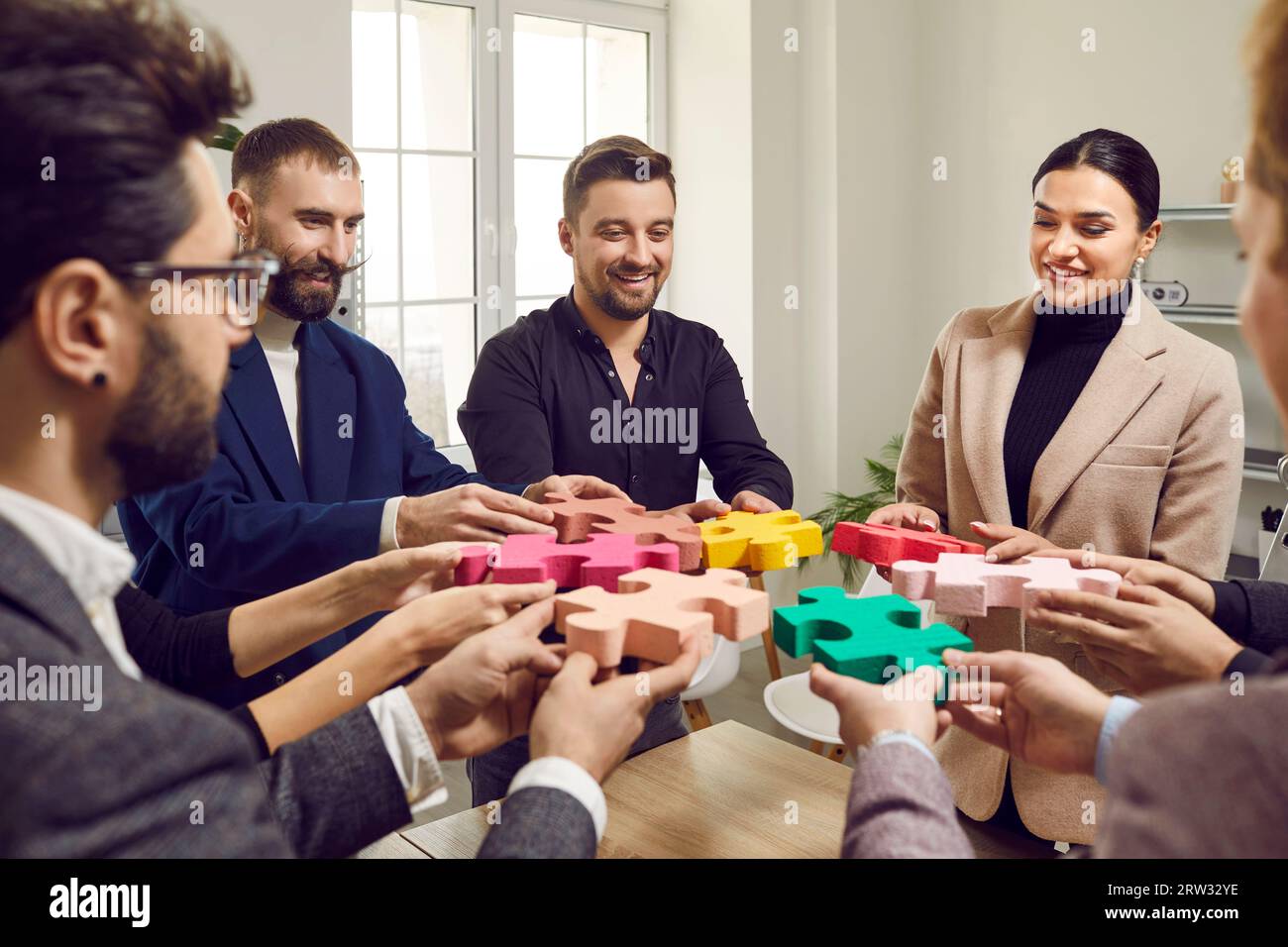 Team of happy people connecting jigsaw puzzle pieces to show concept of ...