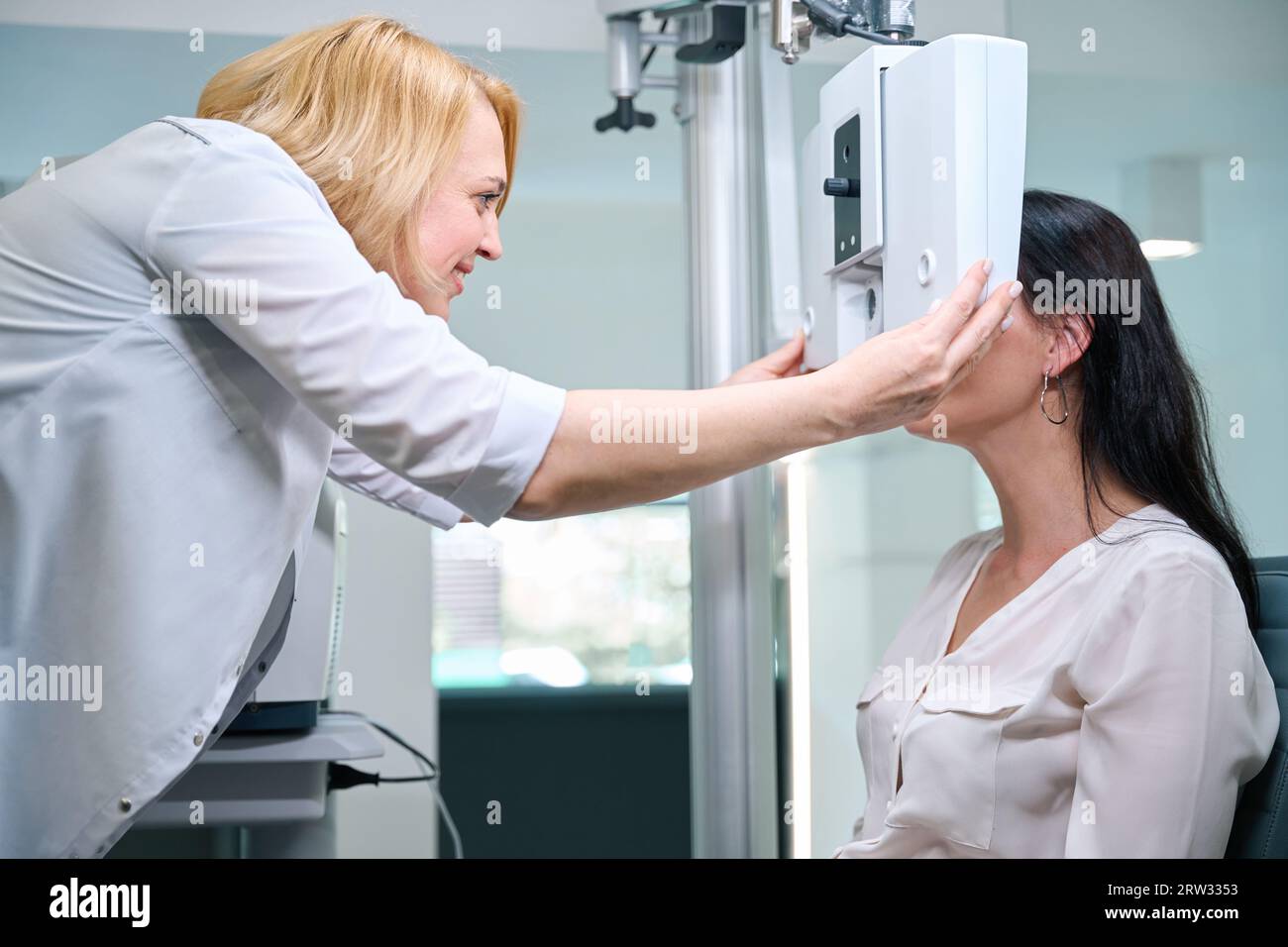 Experienced optometrist preparing female client for digital refraction ...