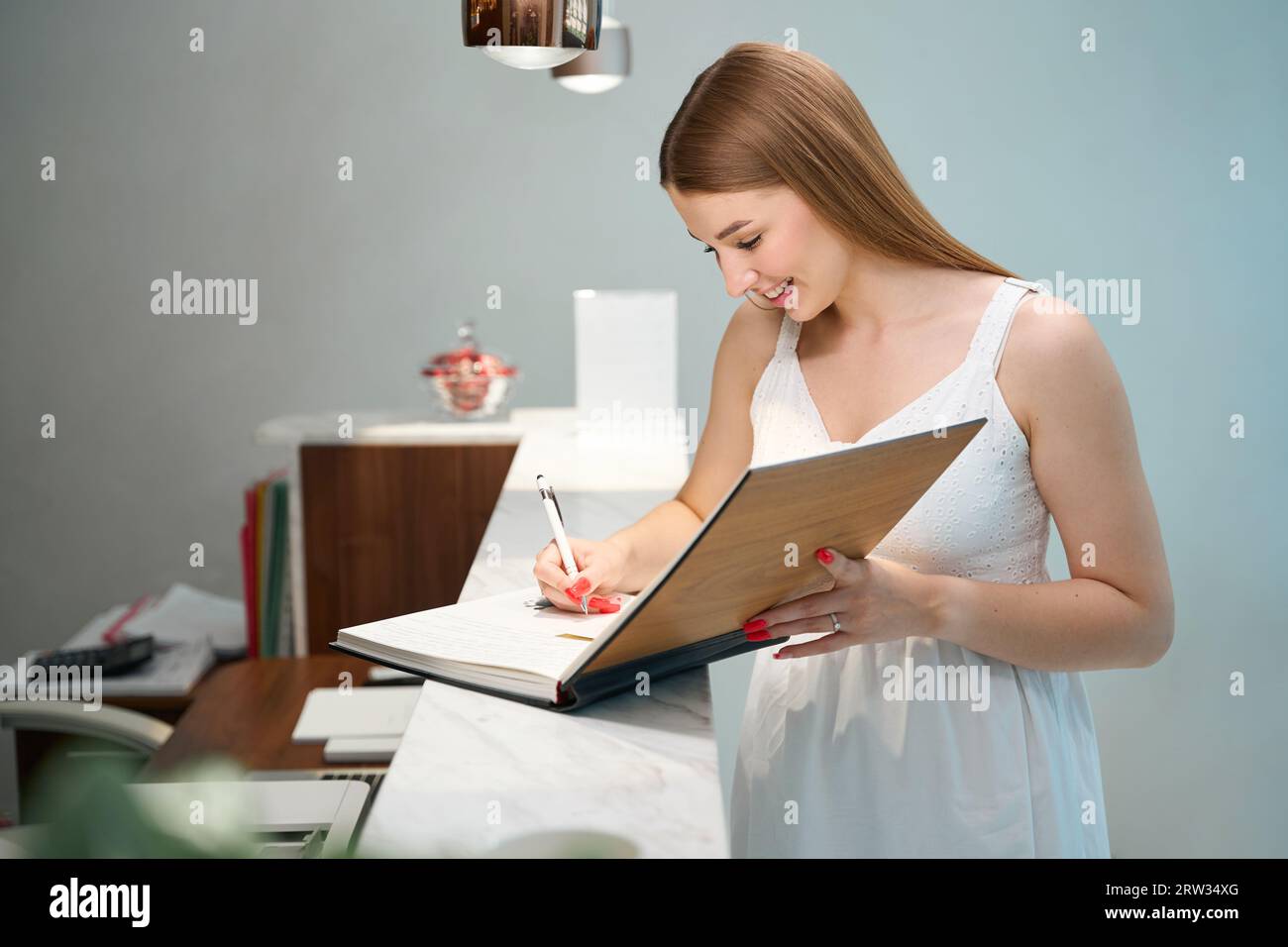 Young woman signing documents at the reception desk Stock Photo - Alamy