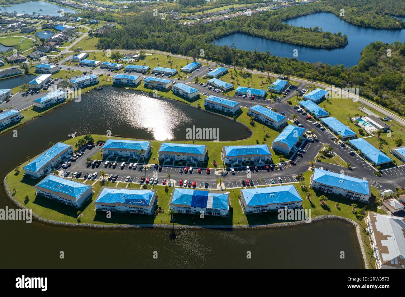 Hurricane damaged apartment buildings rooftops covered with protective plastic tarp against rain ...
