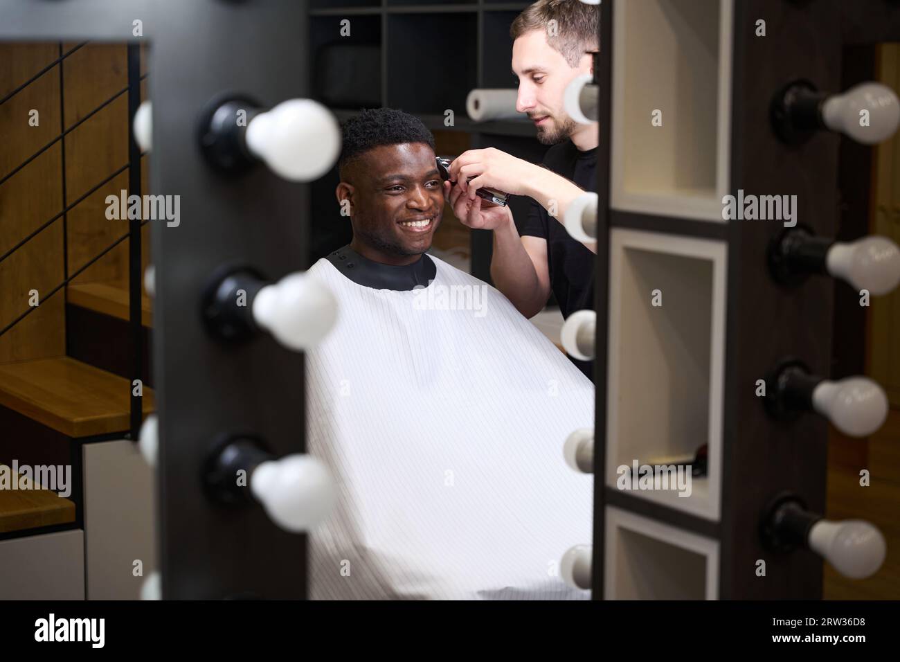 Master cuts clients hair in front of mirror in barbershop Stock Photo ...